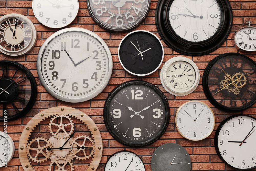 Collection of clocks hanging on red brick wall Stock Photo | Adobe Stock