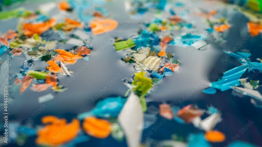 Microplastics on the surface of polluted water. Concept of global ...