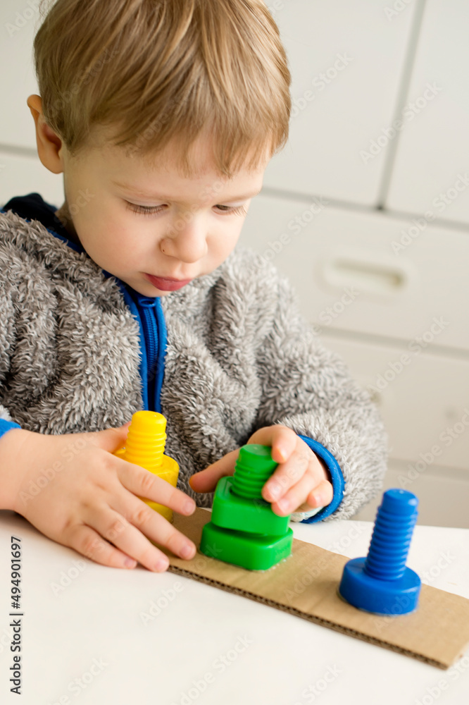 Shapes, colors and fine motor skills. toddler turns the nut on the bolt ...