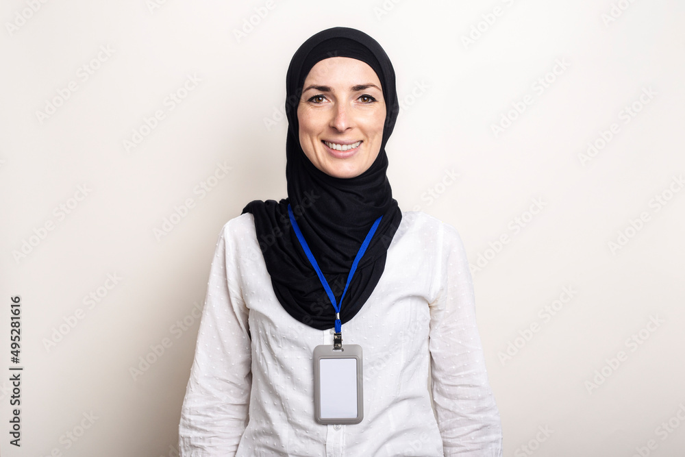 Young Muslim woman in white shirt and hijab with office badge. Work for ...