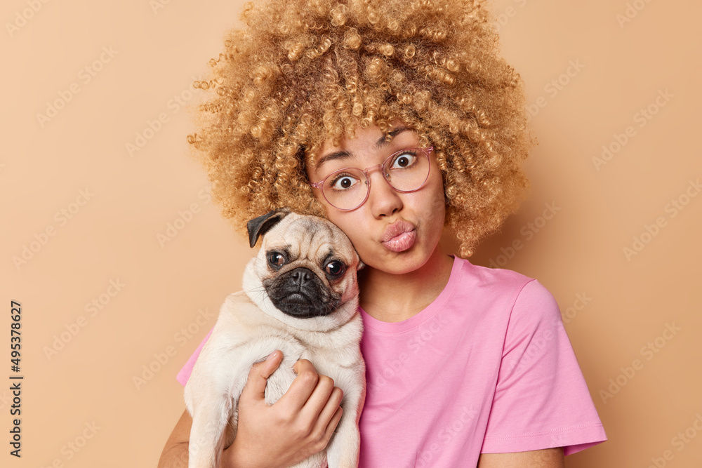Lovely young woman poses with pug dog expresses love and care to ...
