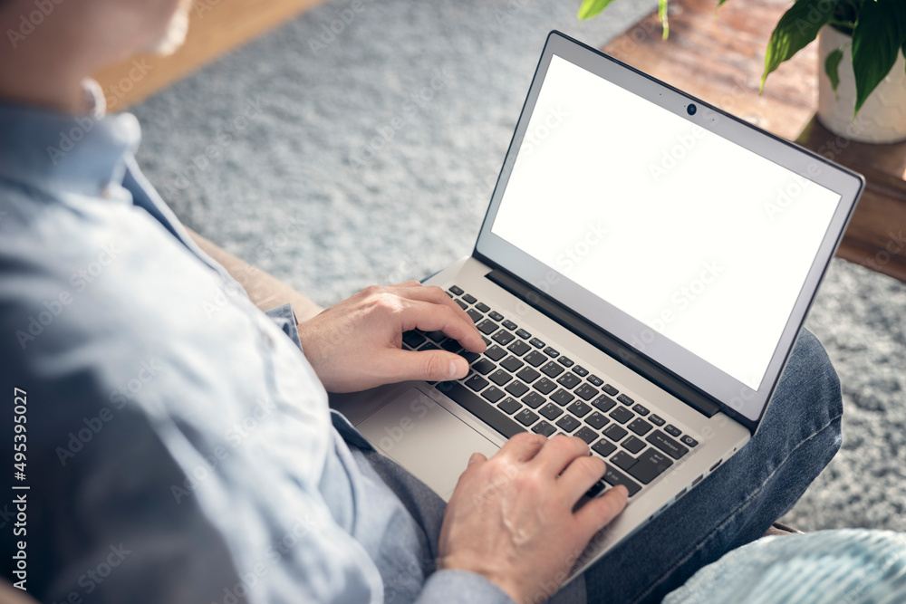 Laptop computer on mans lap working from home or in office with blank ...
