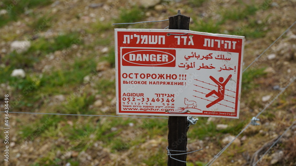 Photo Stock Electric fence danger warning sign. Written in three ...