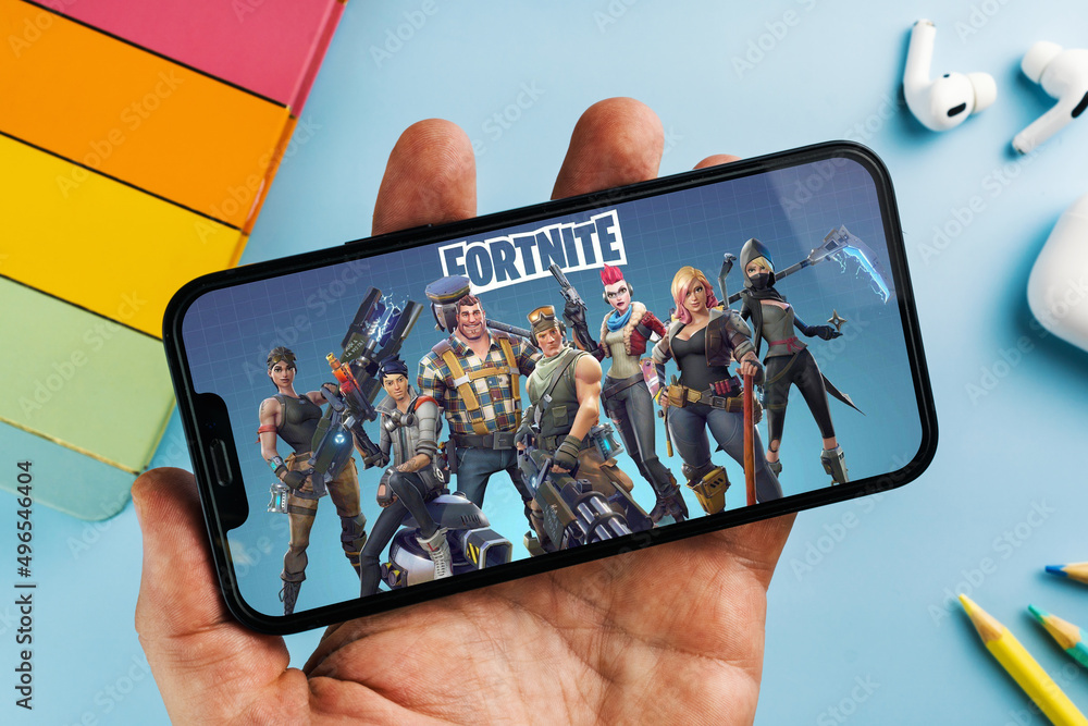 Man holding a smartphone with Fortnite mobile game app on the screen ...