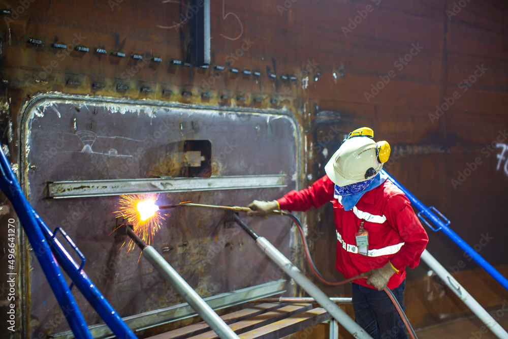 Male worker preheating It involves heating the shell plate metal tank ...