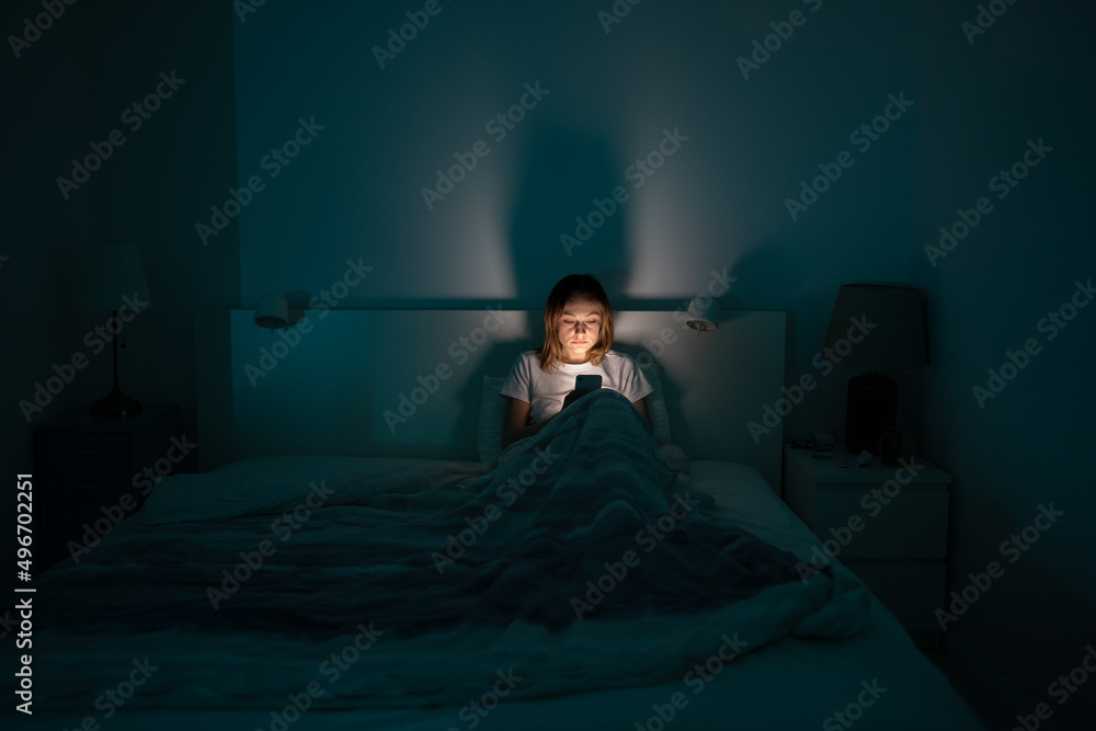 Foto Sleepy exhausted woman lying in bed using smartphone, can not sleep. Insomnia, addiction ...