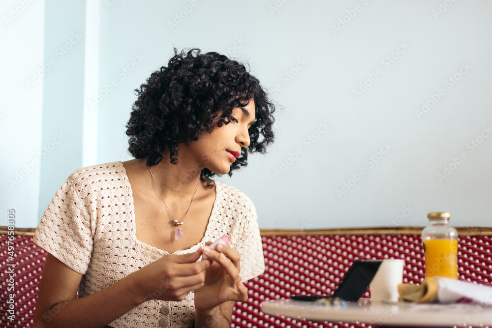 Young trans woman putting on makeup in a cafe Stock Photo | Adobe Stock
