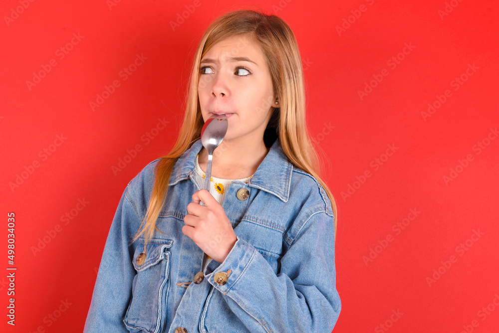Very hungry blonde little kid girl wearing denim jacket over red ...