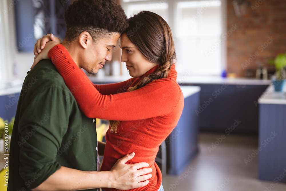 Side view of young biracial romantic couple embracing while dancing in ...