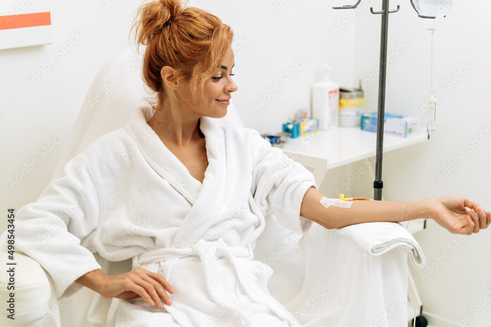 Woman sitting in armchair and closed eyes while receiving IV infusion ...