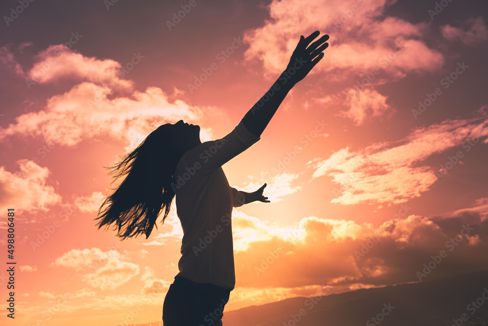 Woman looking up to the sunrise sky with open arms. People with ...