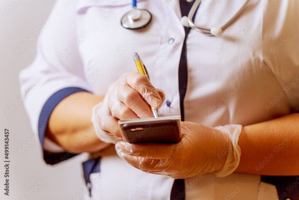 Female doctor writes something on a small sheet of paper for notes ...
