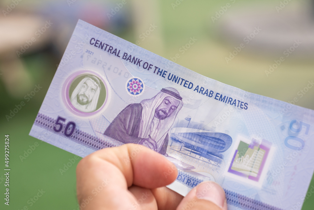 Persons hand giving the Currency of the United Arab Emirates (UAE ...