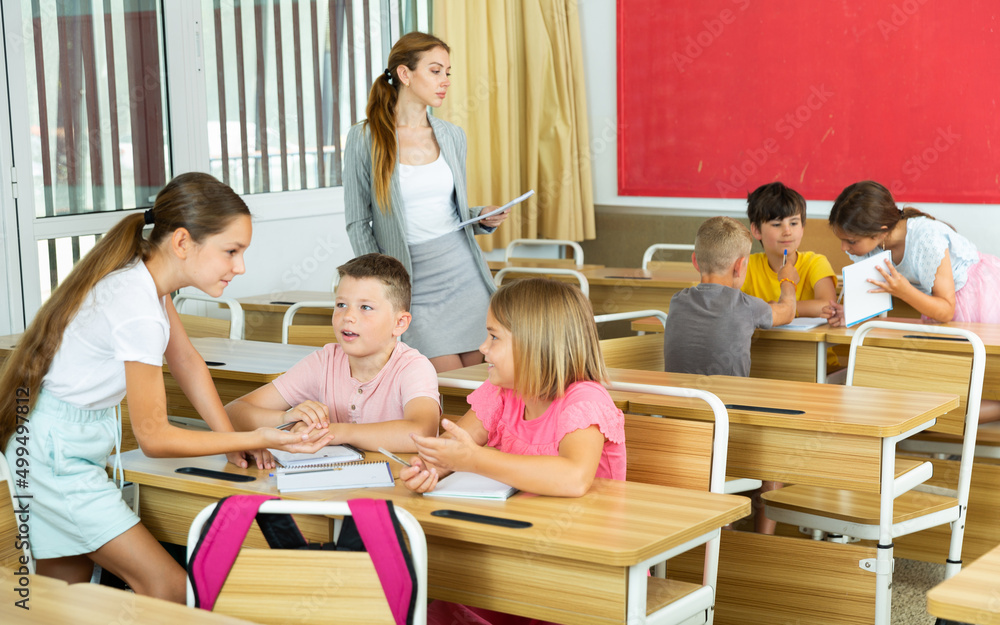 Interested preteen pupils divided into small groups, discussing ...