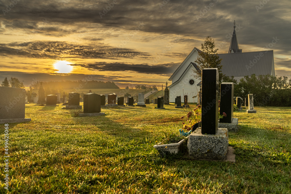 Cemetery gravestones and a church in a dark mood as the sun rising over ...