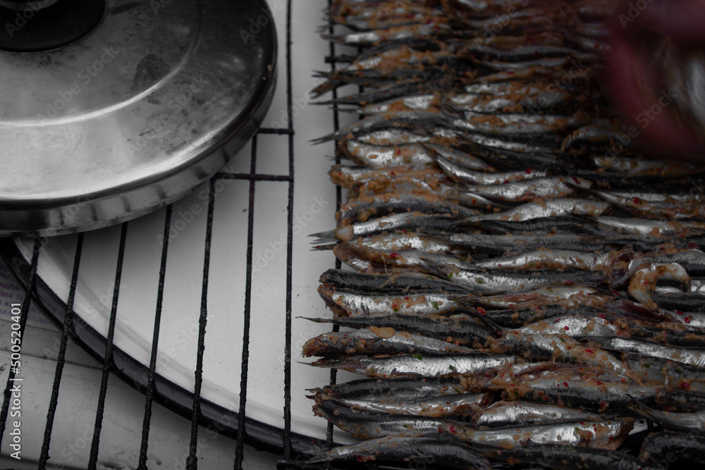 Preparation for grilling anchovies on charcoal. Ordered fishes in rows ...