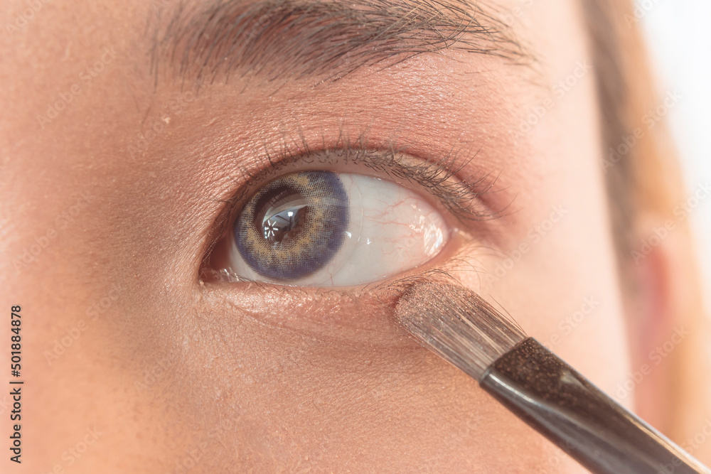 Closeup of applying eyeshadow to a lower eyelid of a young asian woman ...