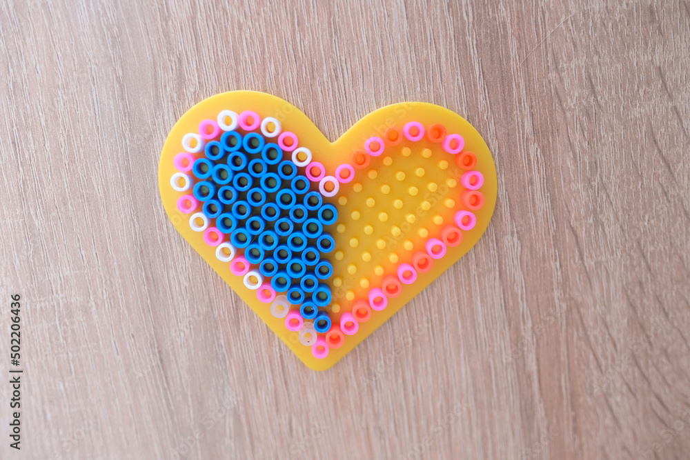 Stock-Foto „close-up of blue yellow heart, creating perler bead ...