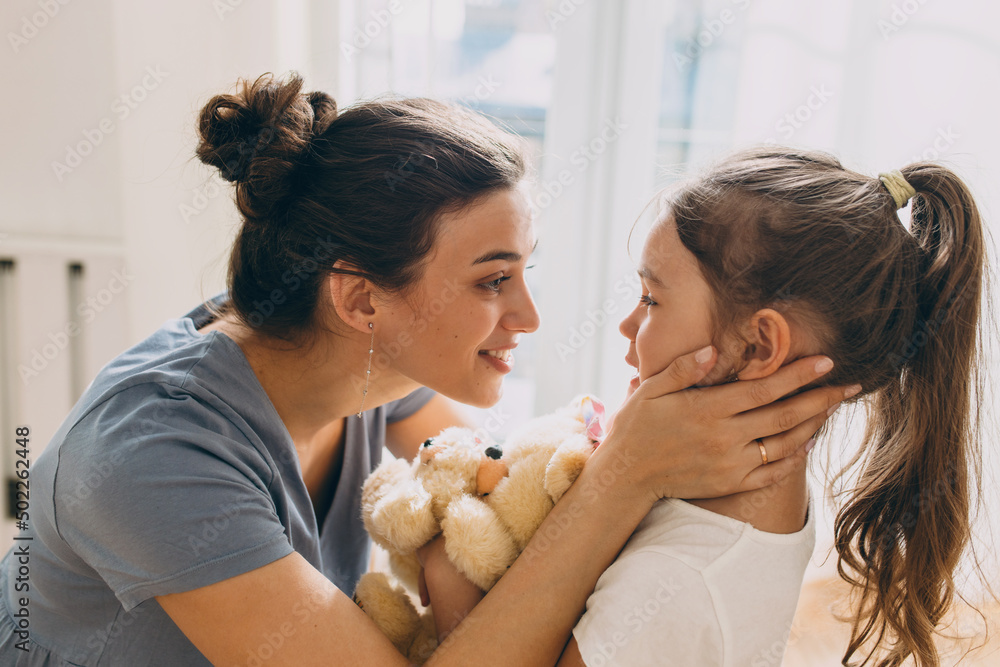 Adorable charming mom of 20s with cute hair bun dressed in grey casual ...