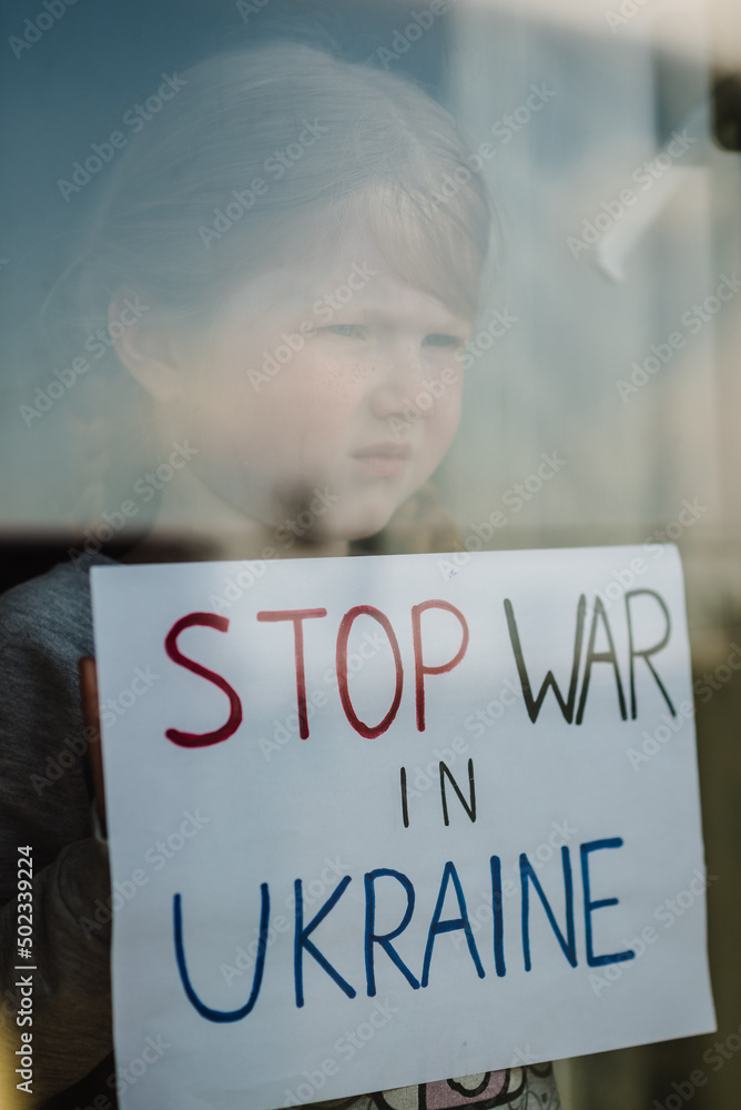 Child at the window and calls No War. Poor girl protesting war conflict ...