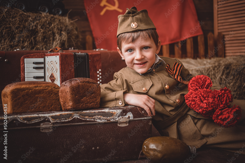 portrait of a smiling child boy in a soldier's suit with a cap in the ...