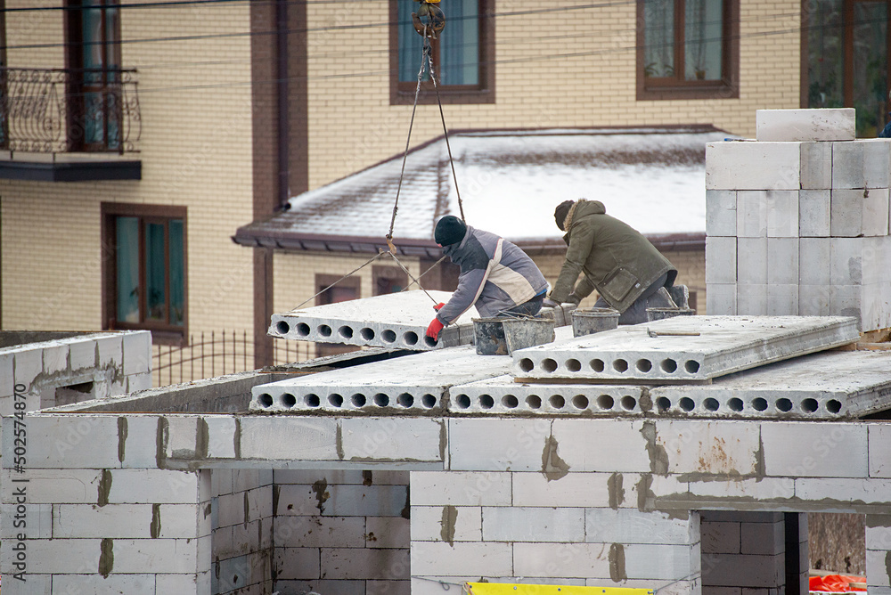 Builder worker installing concrete floor slab panel at building ...