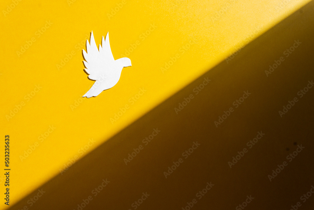 White paper dove bird as a symbol of peace isolated on yellow ...