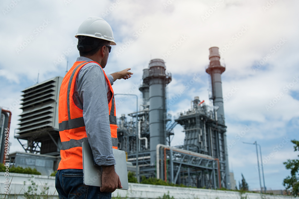 Engineer working and hand hold laptop at Power plant. People in PPE ...