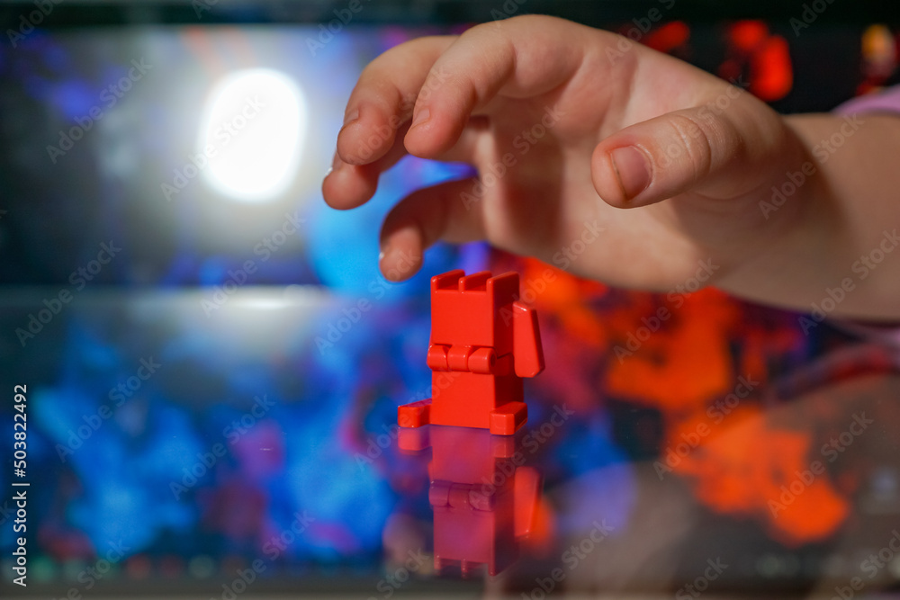 Shallow focus of a child's hand grabbing a red interlocking plastic ...
