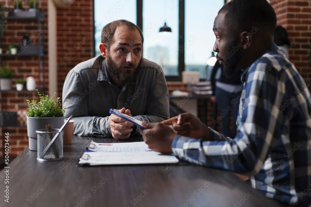 Executive manager interviewing confident man while reviewing CV and ...