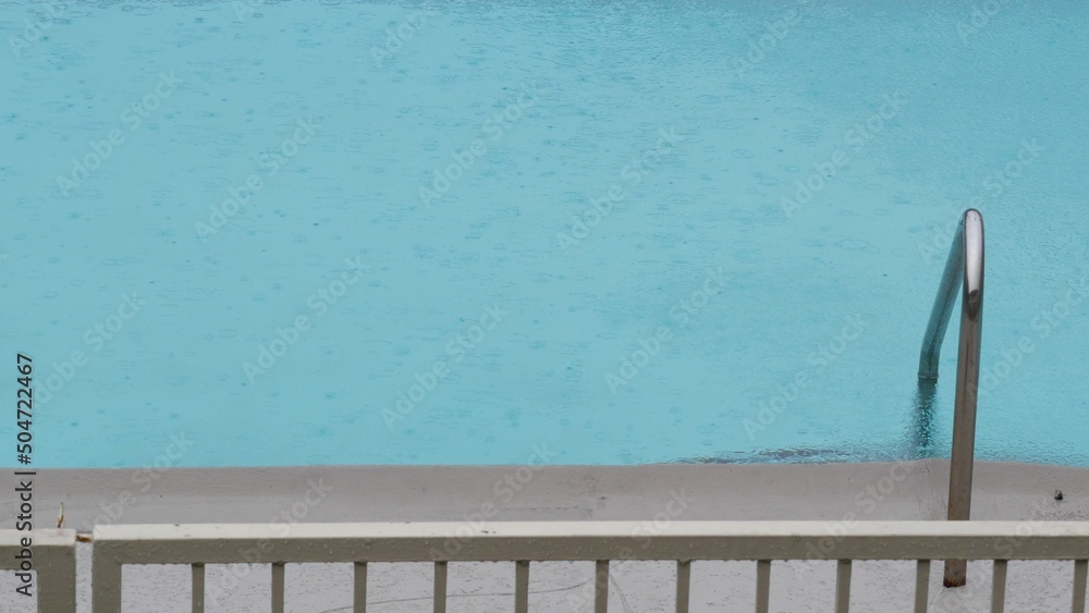 Rain drops falling on water surface of blue swimming pool, rainy day in ...