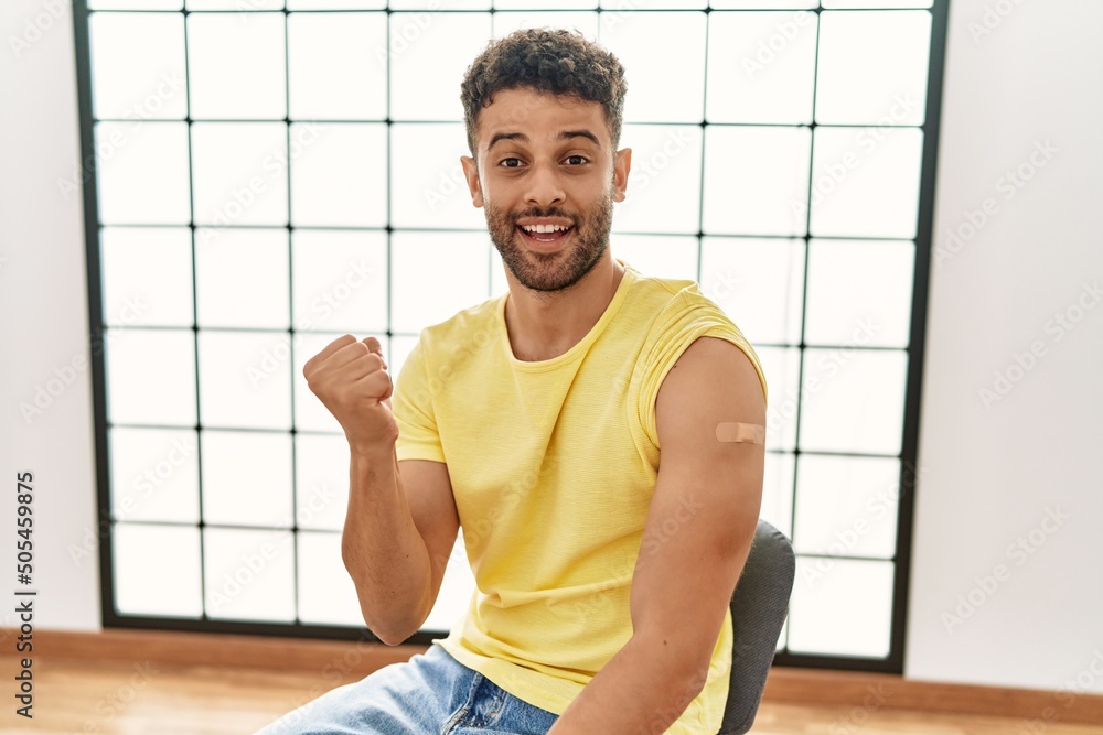 Arab young man getting vaccine showing arm with band aid screaming ...