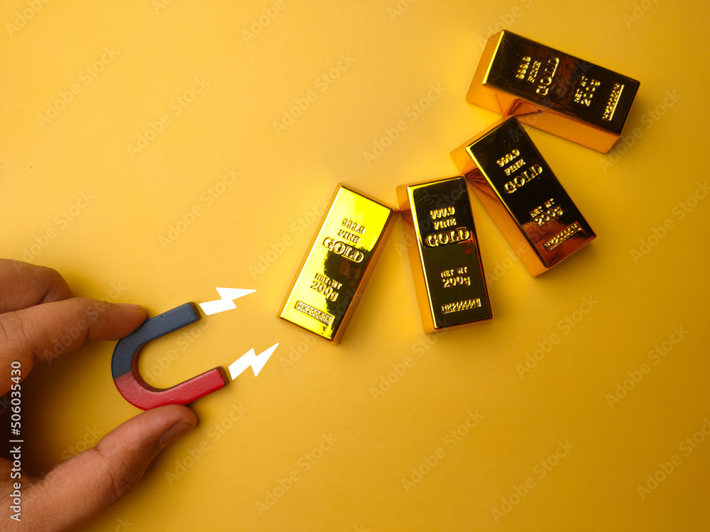 Hand holding magnet attract the gold bar on a yellow background. Stock ...