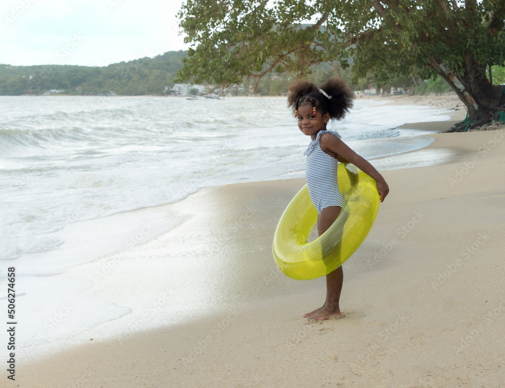 Cute little African girl in striped swimsuit with yellow inflatable ...