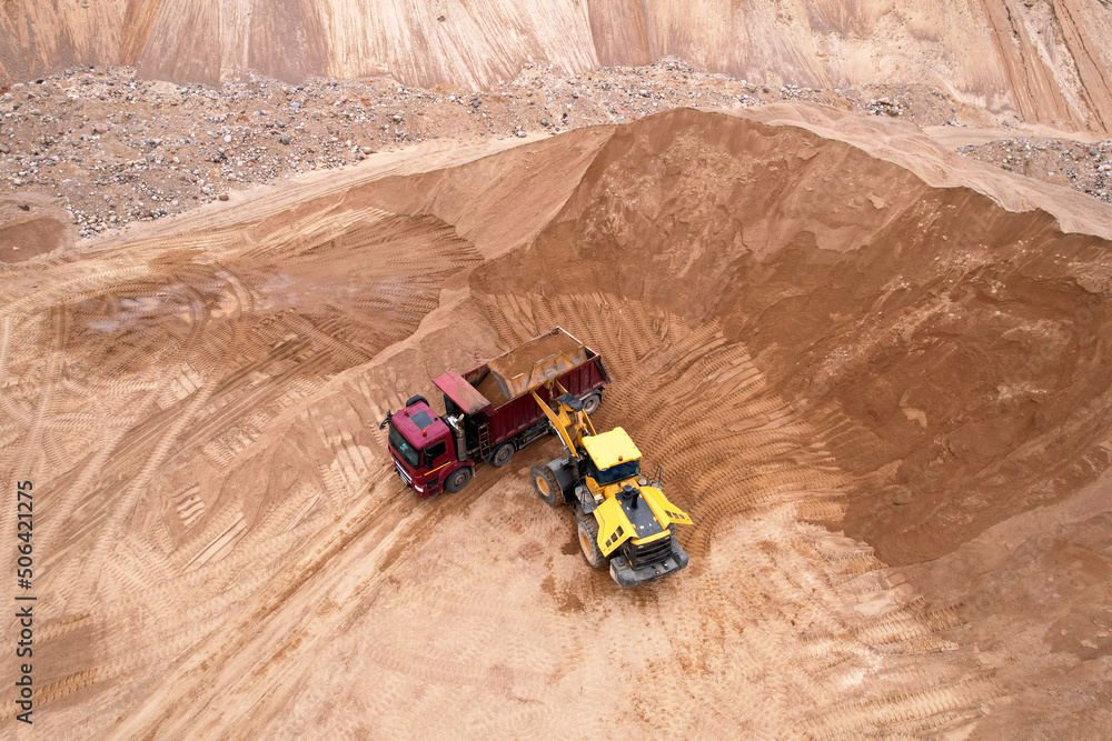 Wheel loader load sand in dump truck in open pit. Front end loader on ...