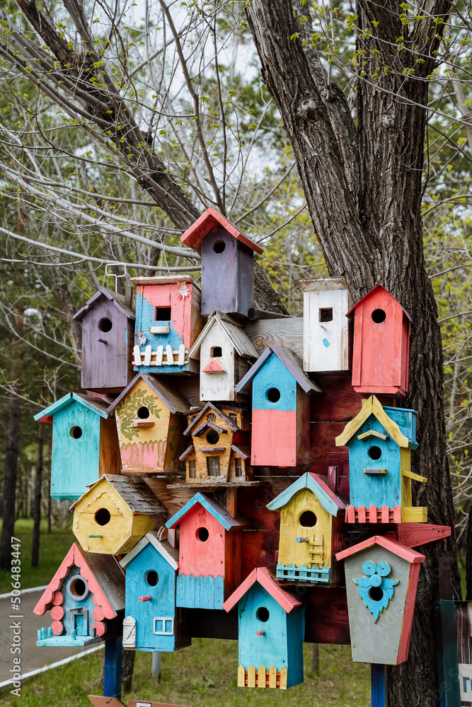 Colorful birdhouses hang on a tree, a group of bird's nests are made of ...