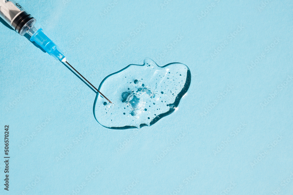 Disposable syringe with a transparent gel-like liquid on a blue ...