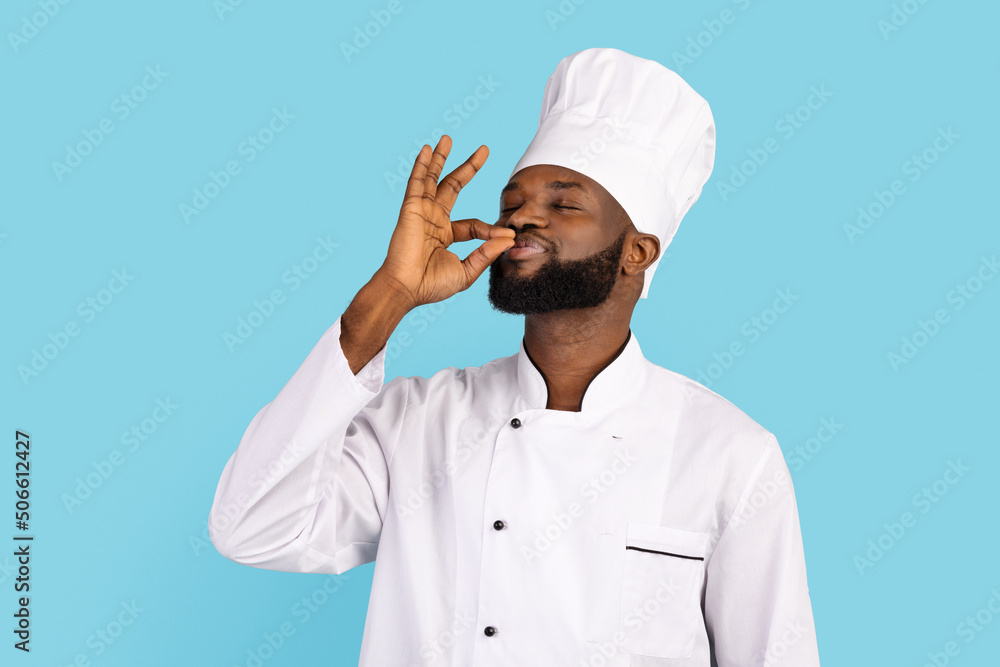 Handsome Black Male Chef In Uniform Kissing Fingers, Standing Over Blue ...