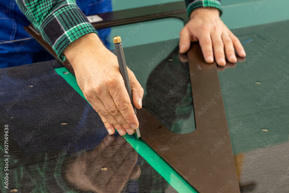 cutting glass, Glazier manually cuts the glass to size using ...