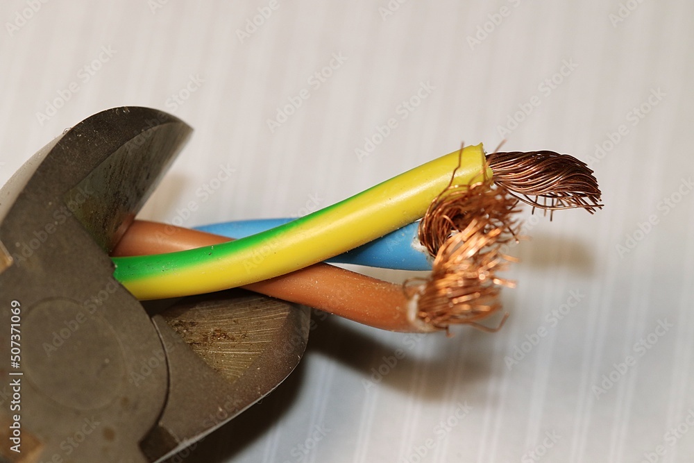 Electrical wires in the process of being cut with a side cutter. The ...