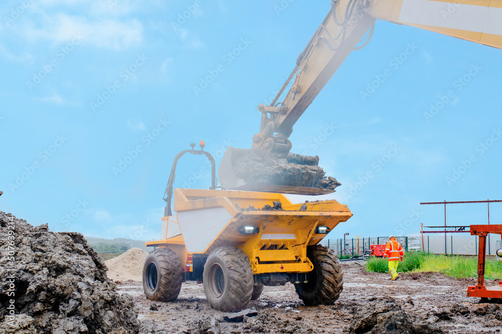 Excavator under rain loading dumper truck with as dug materials during ...