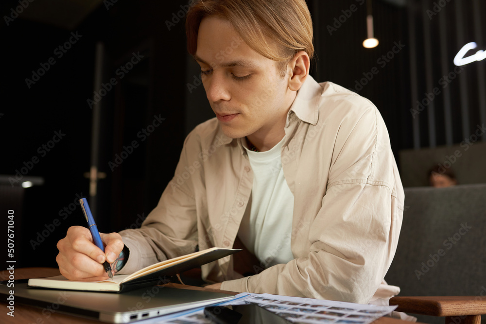 Indoor portrait of serious concentrated Caucasian man writing in ...