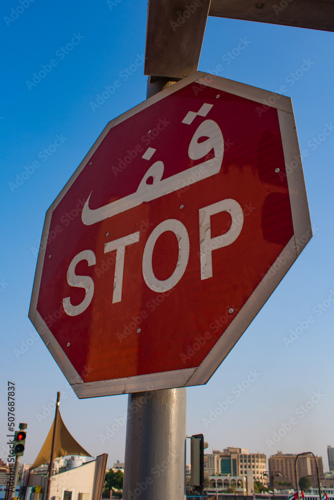 Dubai, road sign with STOP text in Arabic language seen from below over ...