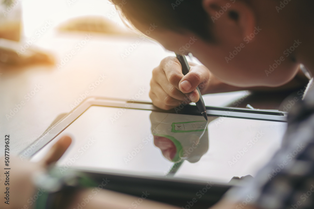 Boy with digital pencil drawing and painting on a tablet at home to ...