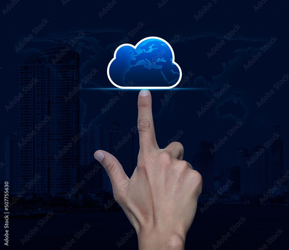 Hand click on cloud computing icon with copy space over world map, modern city tower and ...