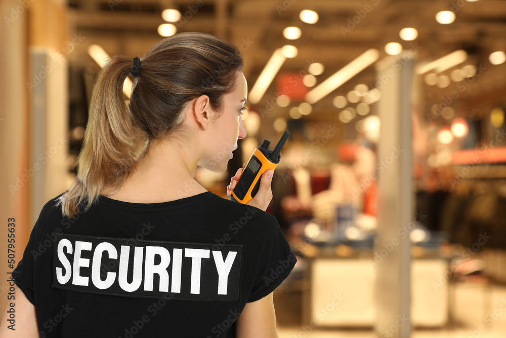 Female security guard wearing uniform using portable radio transmitter ...