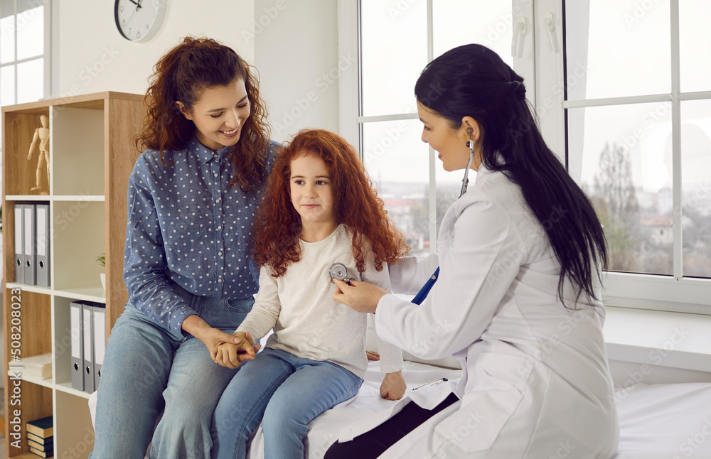 Friendly female pediatrician or nurse using stethoscope listens to ...
