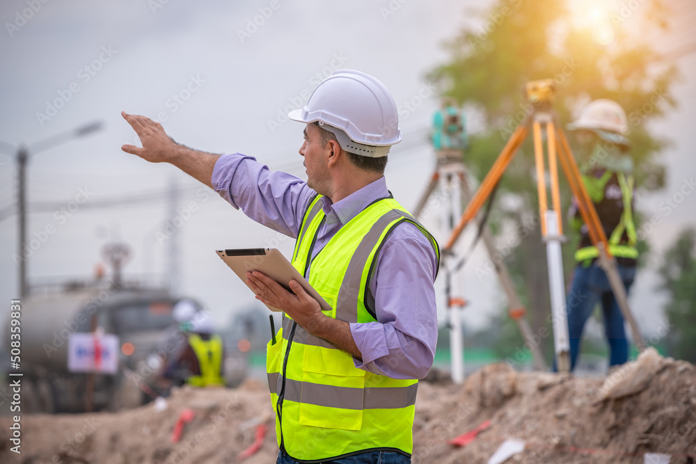 Surveyor engineer wearing safety uniform and helmet with equipment ...