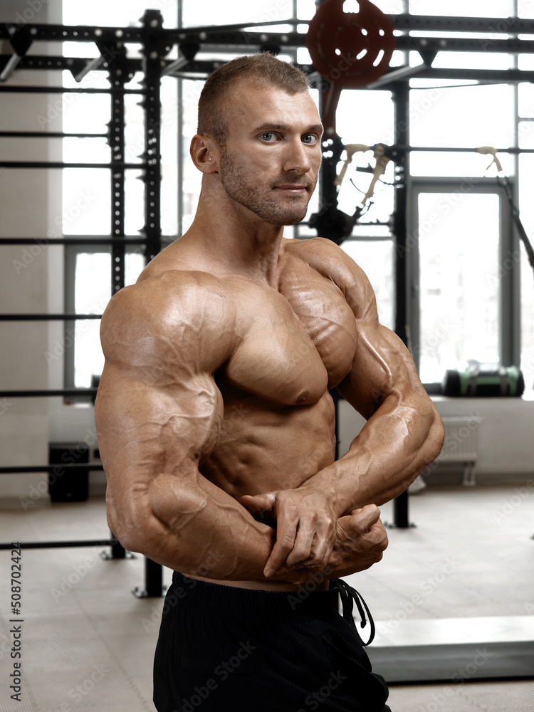 Bodybuilder with perfect physique posing in the gym, demonstrating ...