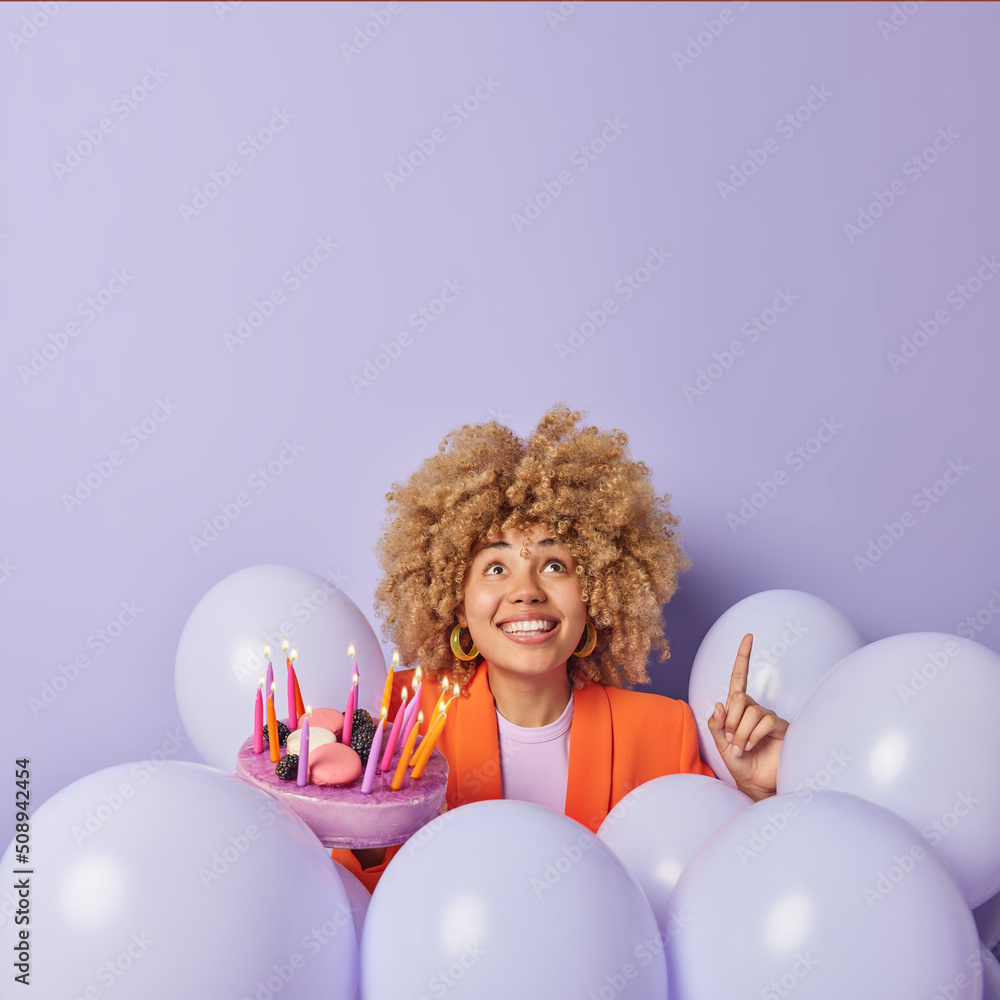 Vertical shot of cheerful young woman with curly hair points index ...
